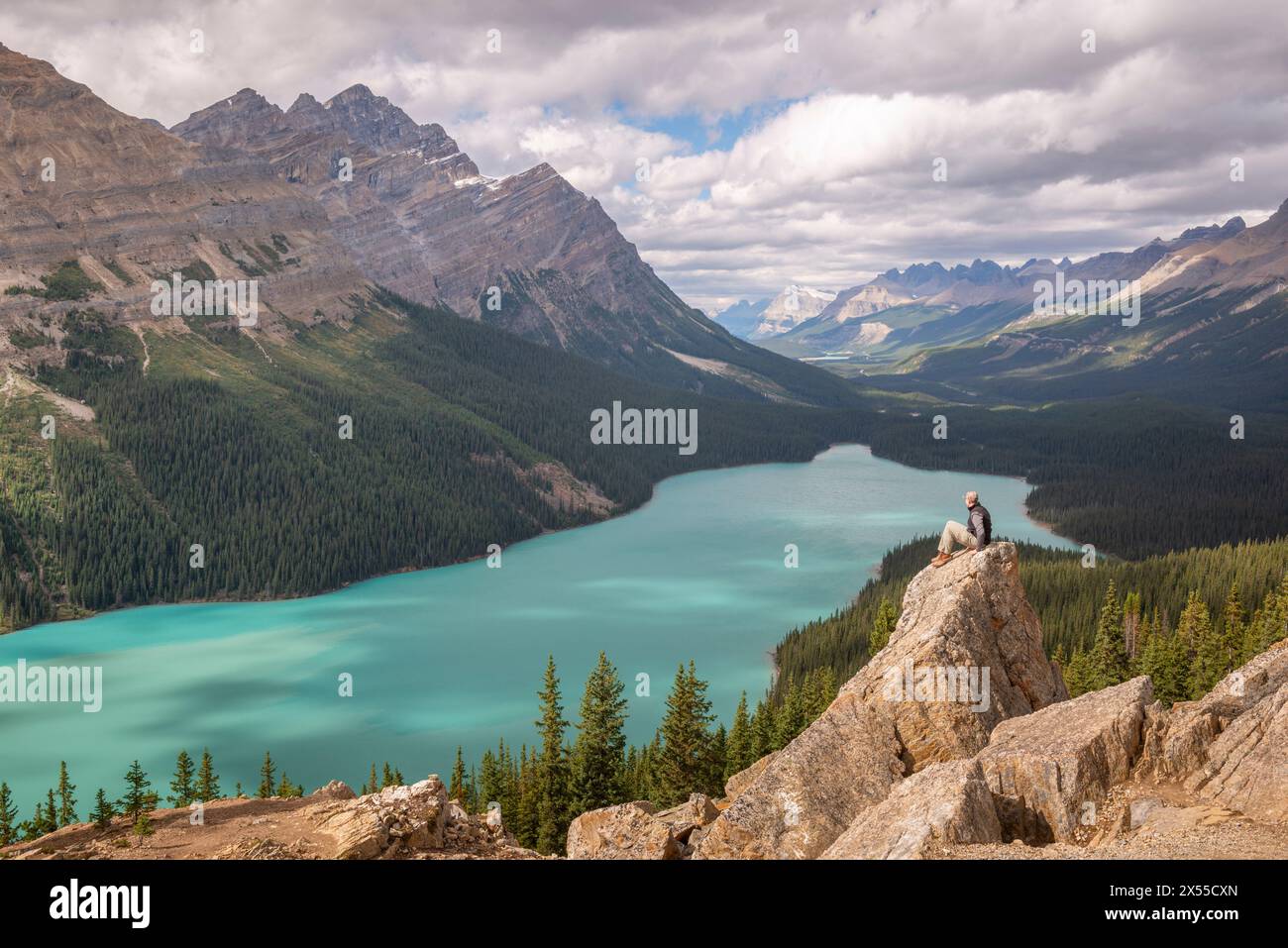 Man sitting on rocks overlooking Peyto Lake in the Canadian Rockies ...