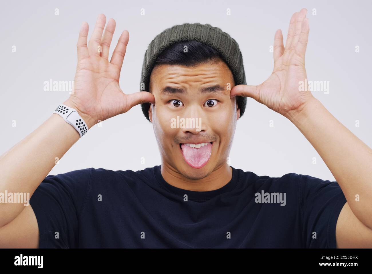 Funny face, portrait and Asian man in studio with tongue out, hands and ...