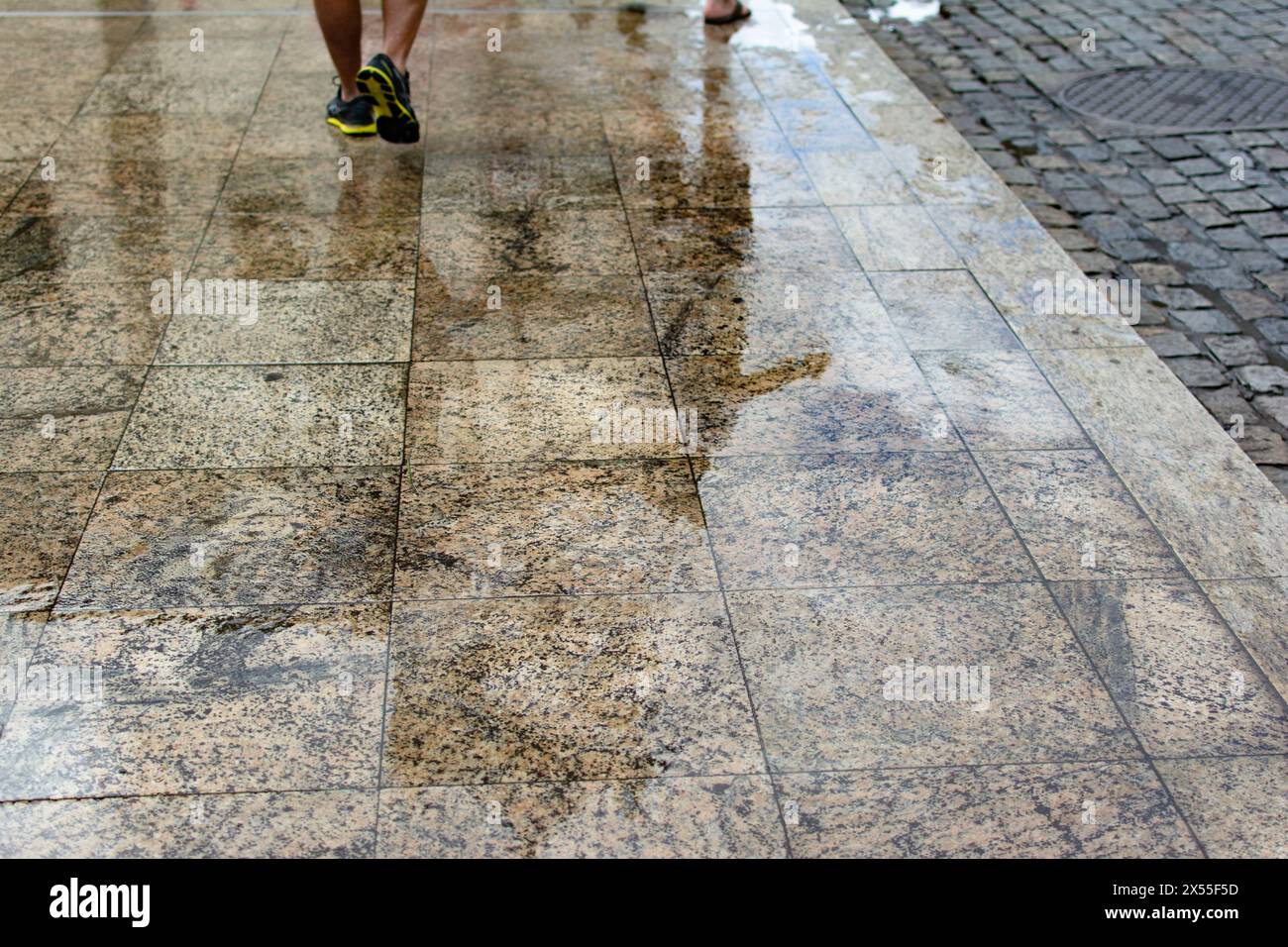 Reflection on the wet ground from the rain of pedestrians passing on ...