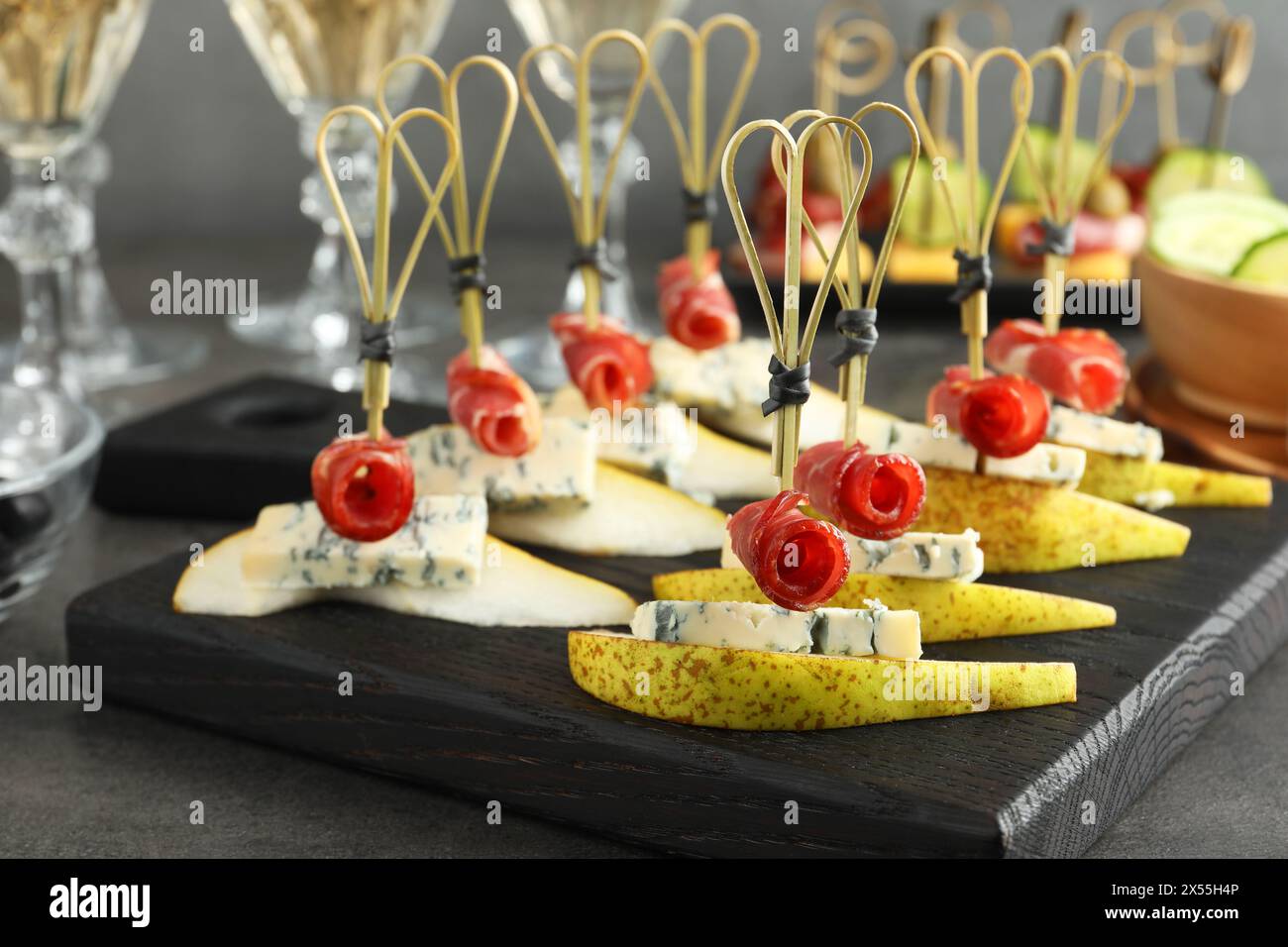 Tasty canapes with pears, blue cheese and prosciutto on grey table ...