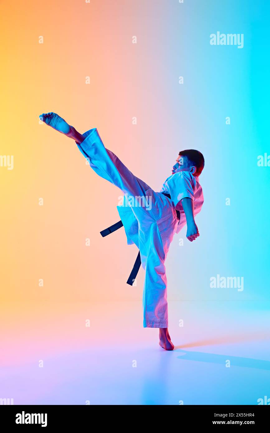 Dynamic image of teen boy, karateka in motion, showing high kick stance ...
