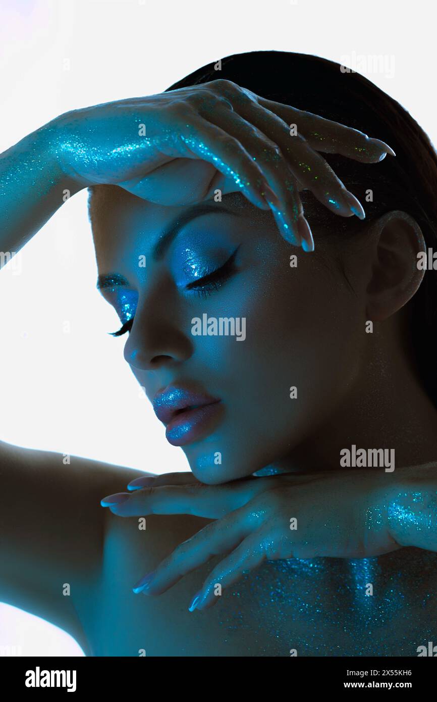 Beauty Woman posing with shimmering blue-tinted skin makeup ...