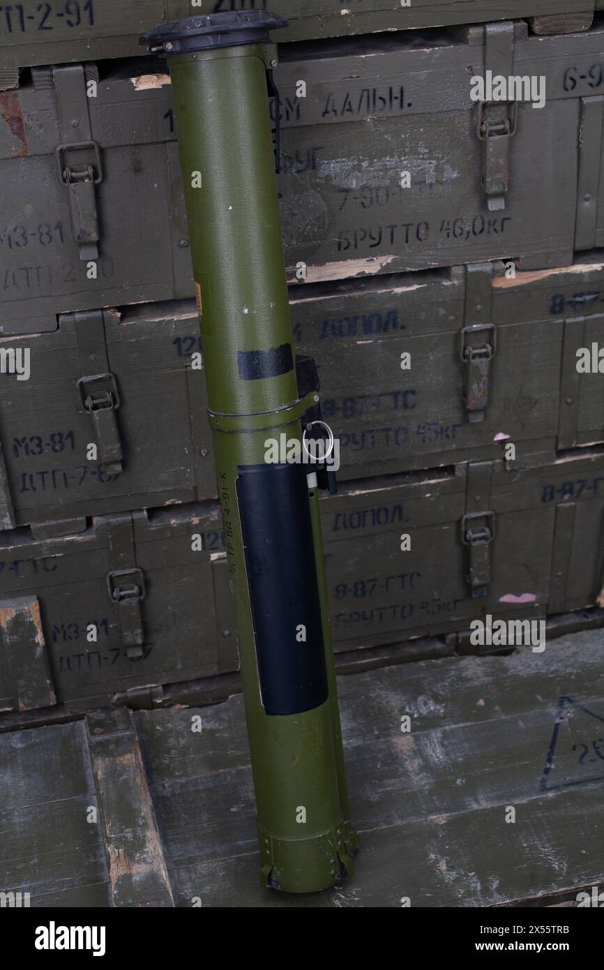 RPG anti-tank rocket propelled grenade launcher with HEAT grenade on army green crate. Text in ...