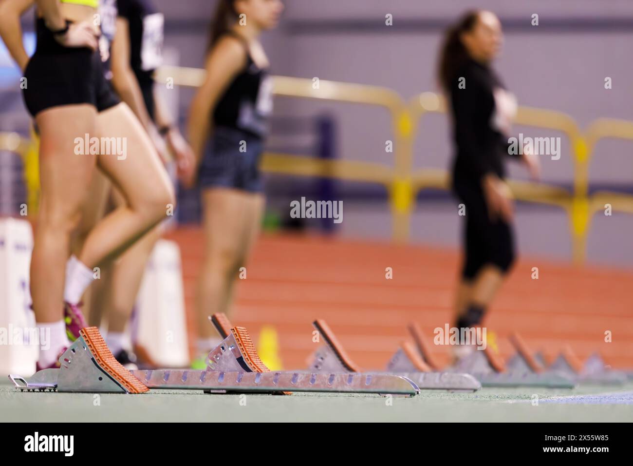 Young sportswomen preparing to start sprint on indoor track and field ...