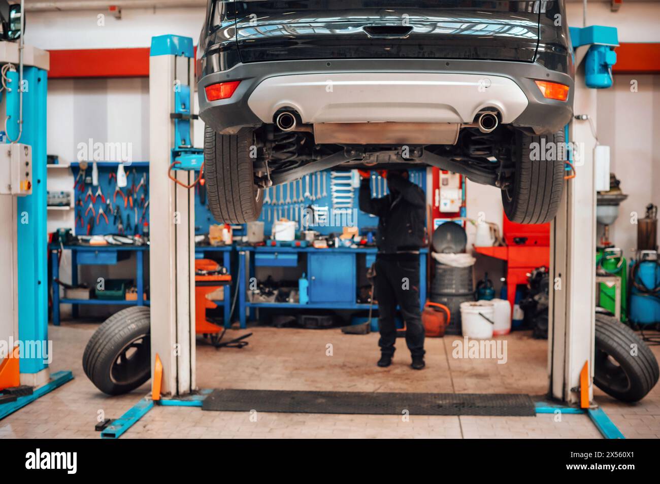Anonymous male mechanic in uniform and gloves while standing working on ...