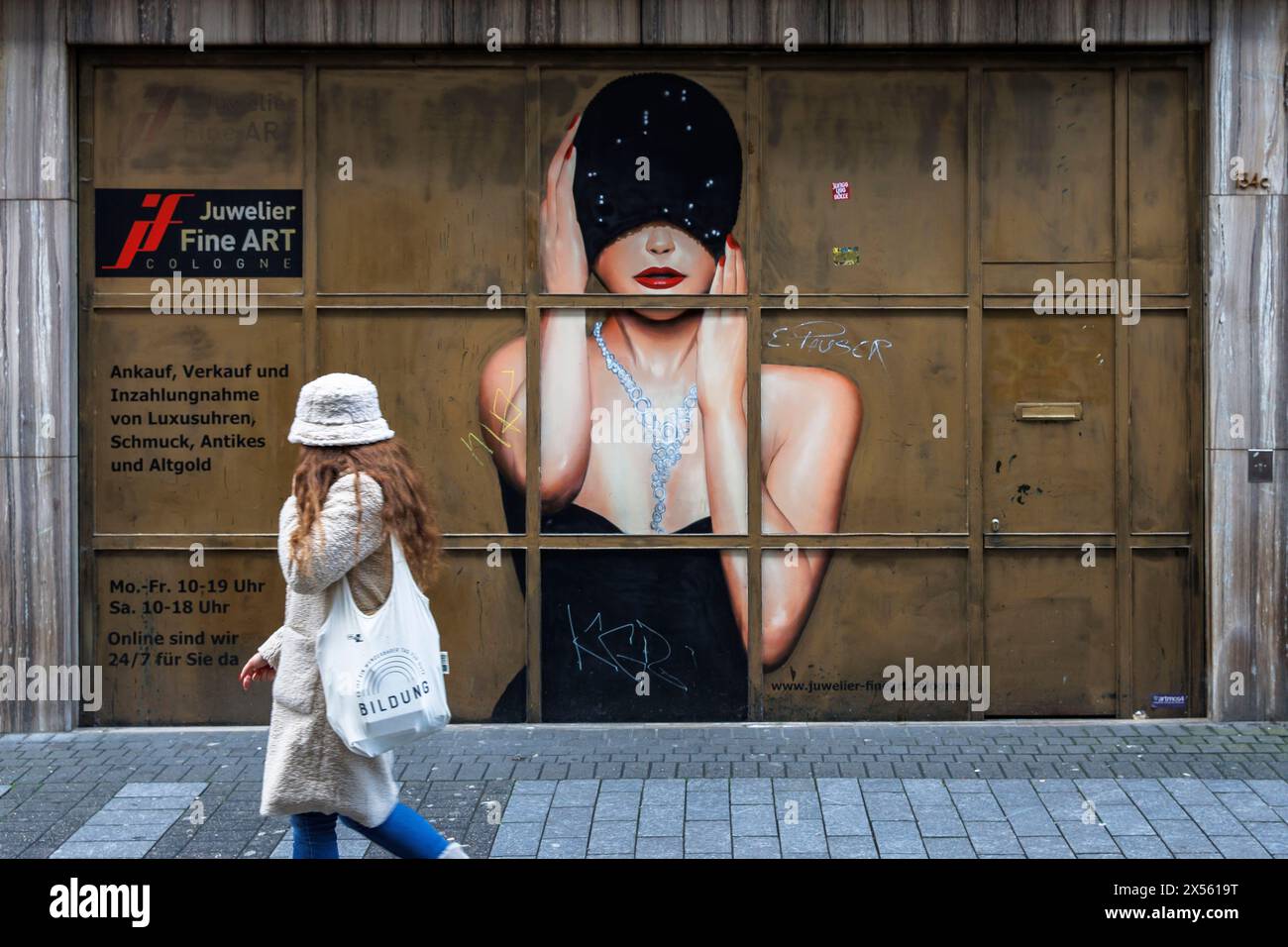 woman passes a billboard of a shop in the shopping street Hohe Strasse ...