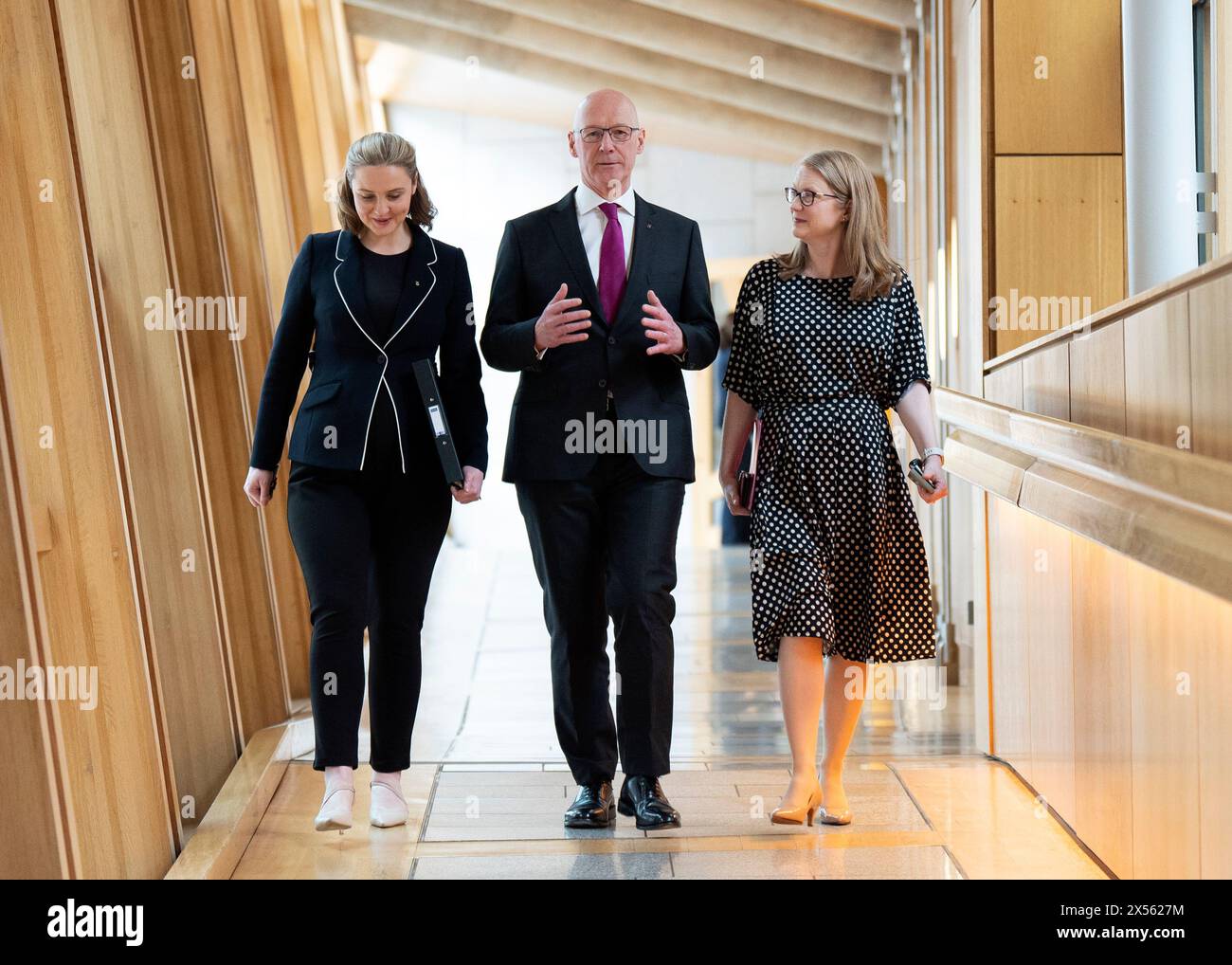 John Swinney leaves the main chamber, along with Mairi McAllan (left ...