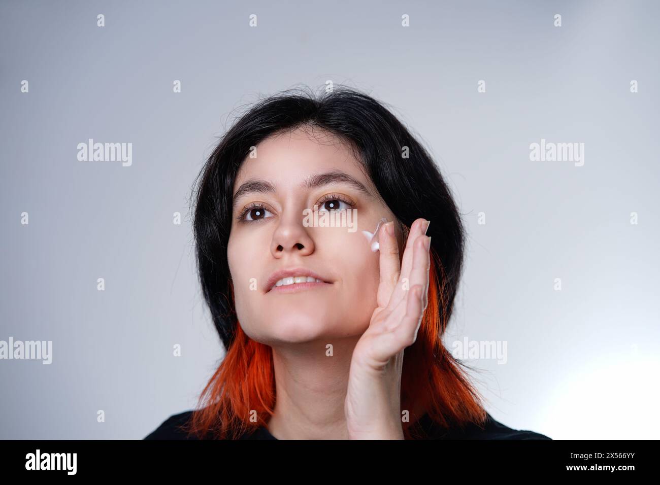 Mediterranean black and orange haired person applying a scoop of ...