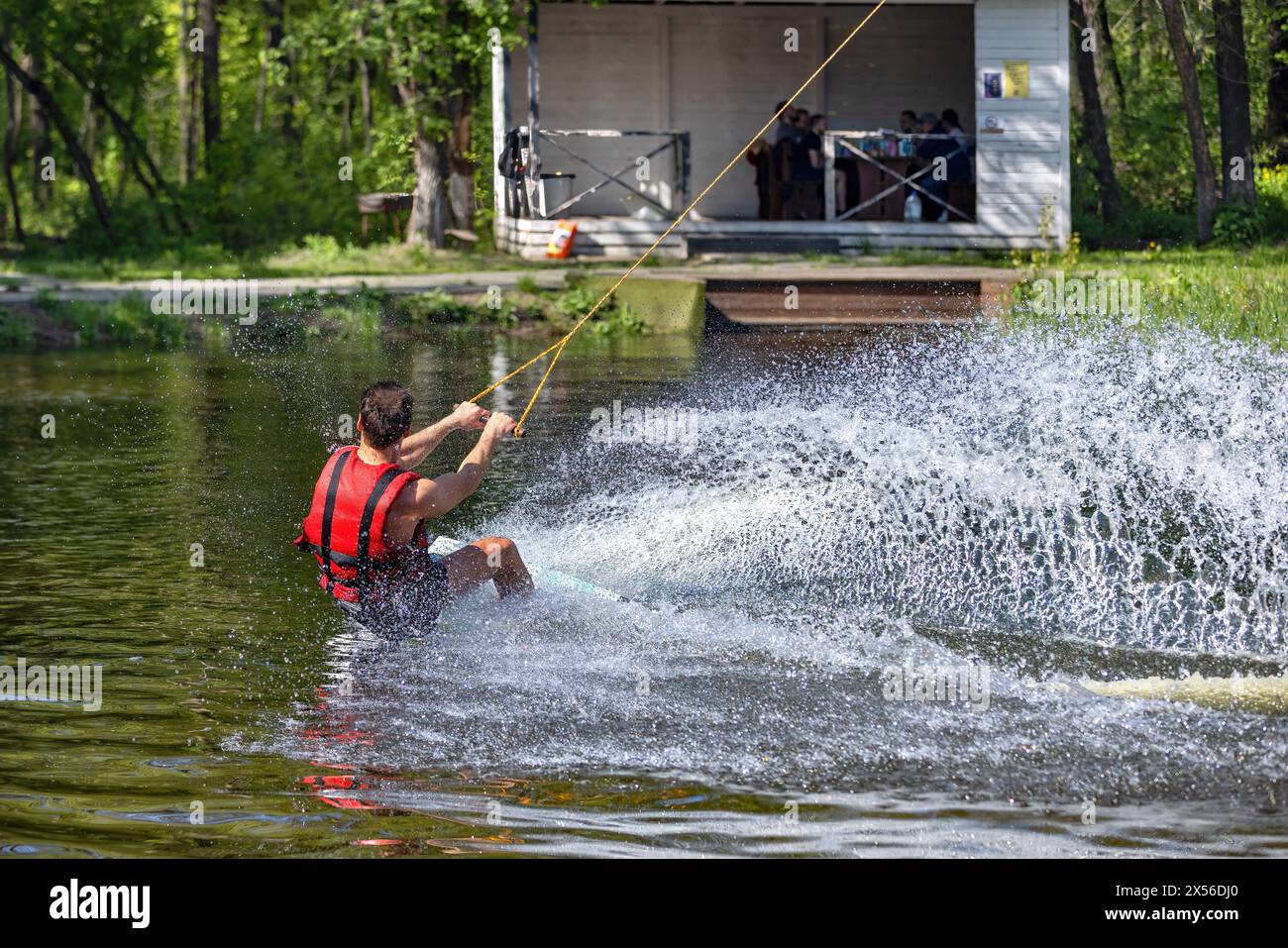 A wakeboarder rushes through the water on a water board along the shore ...