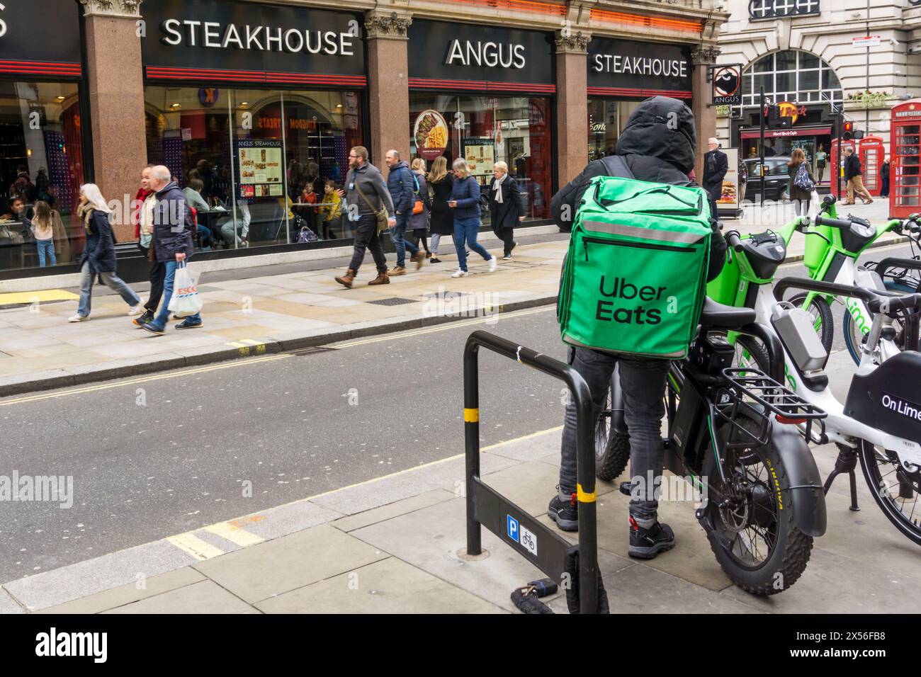 Uber Eats food delivery courier outside an Angus Steakhouse in Central ...