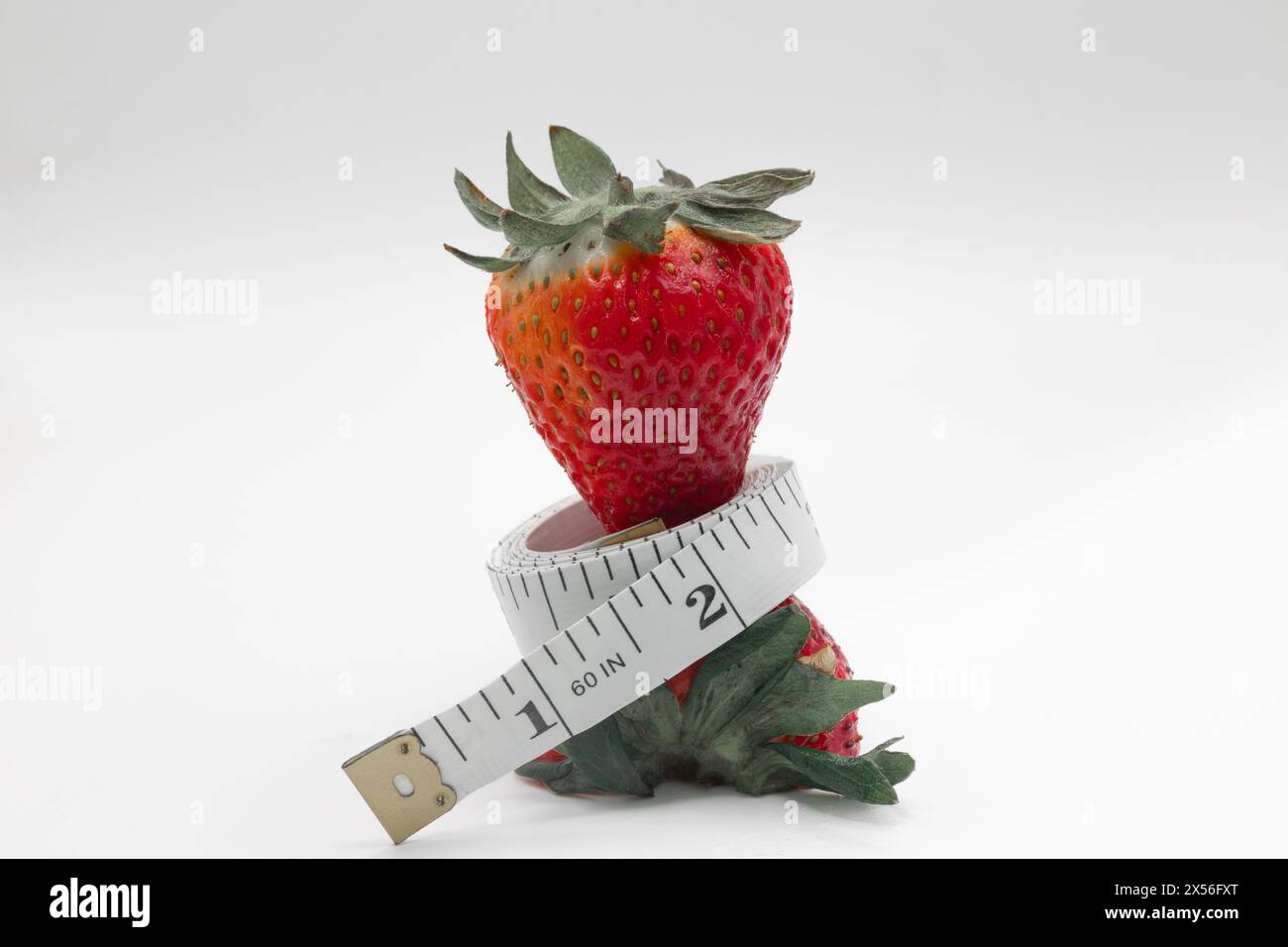 Strawberry suspended vertically with measuring tape excercise weight ...