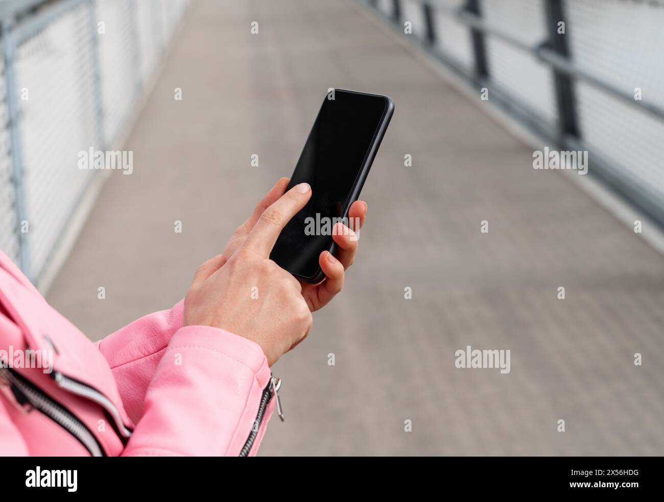 Mobile phone in female hands outdoors. Woman wearing pink jacket ...