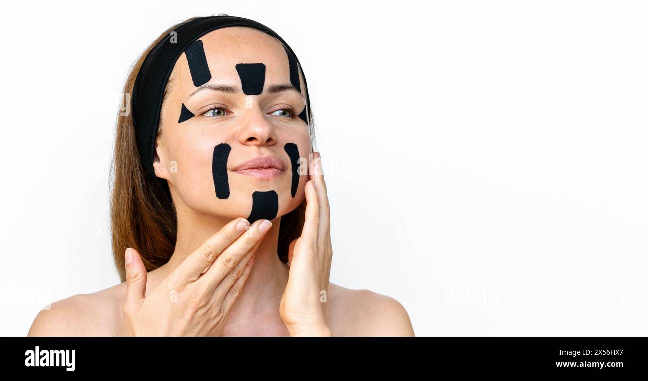Female beauty model applying kinesio facial tapes on her face against a ...