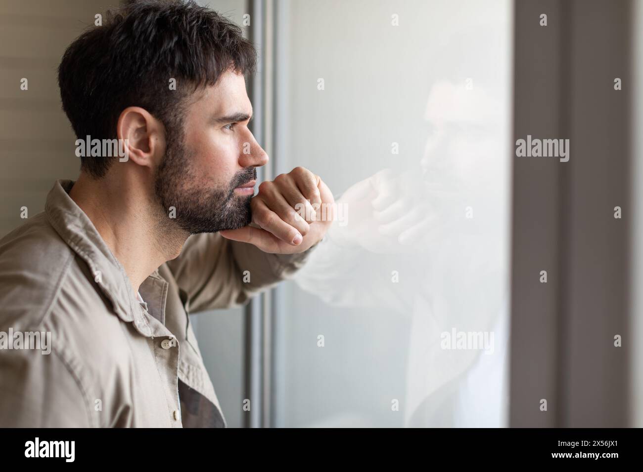 Man Looking Out a Window With Hand on Face Stock Photo - Alamy