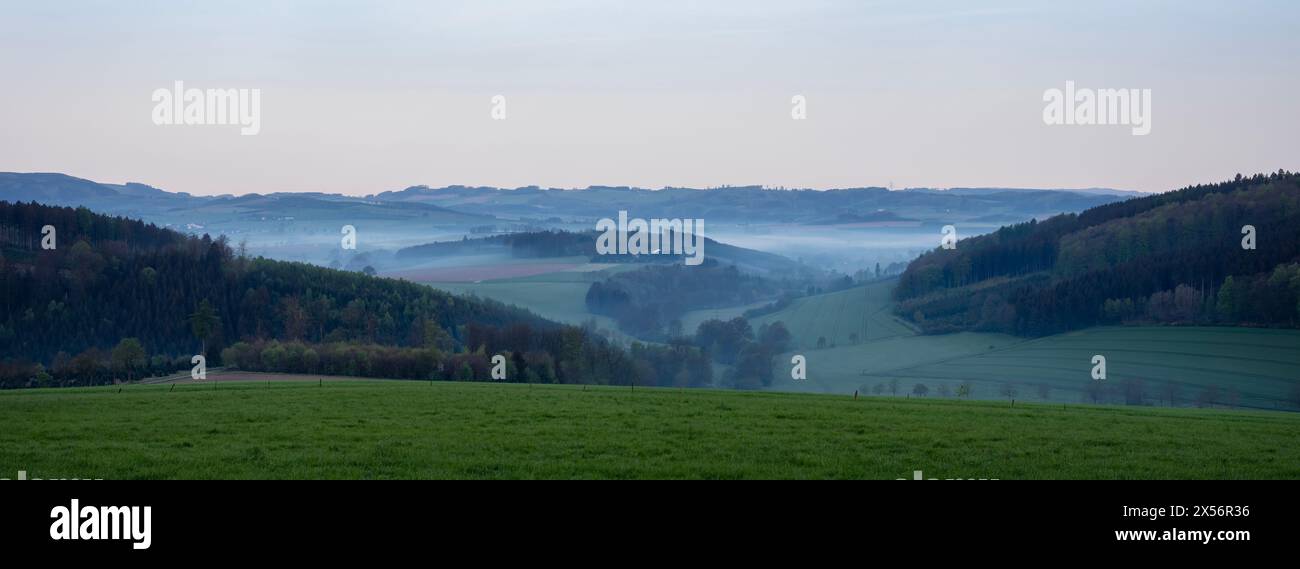 sunrise over early morning landscape with mist in german sauerland ...