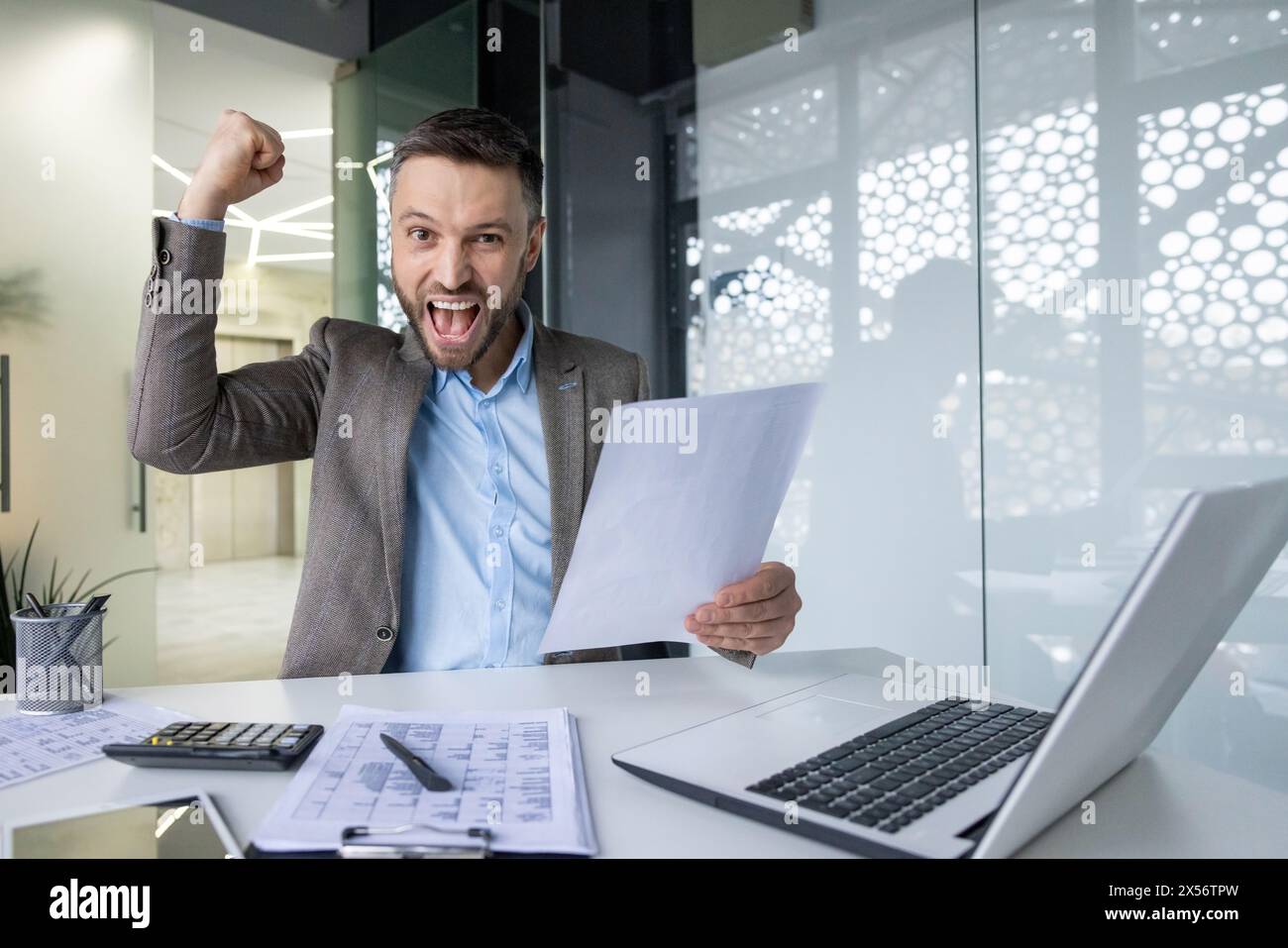Energetic male entrepreneur expressing joy and success in a modern ...