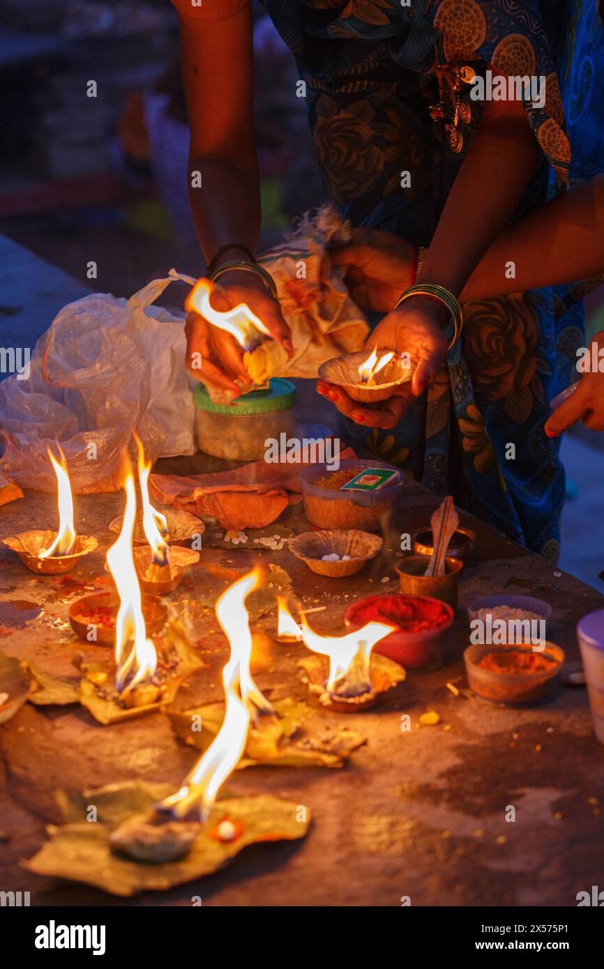 Two women pilgrims in saris lighting oil wicks in small baskets in ...