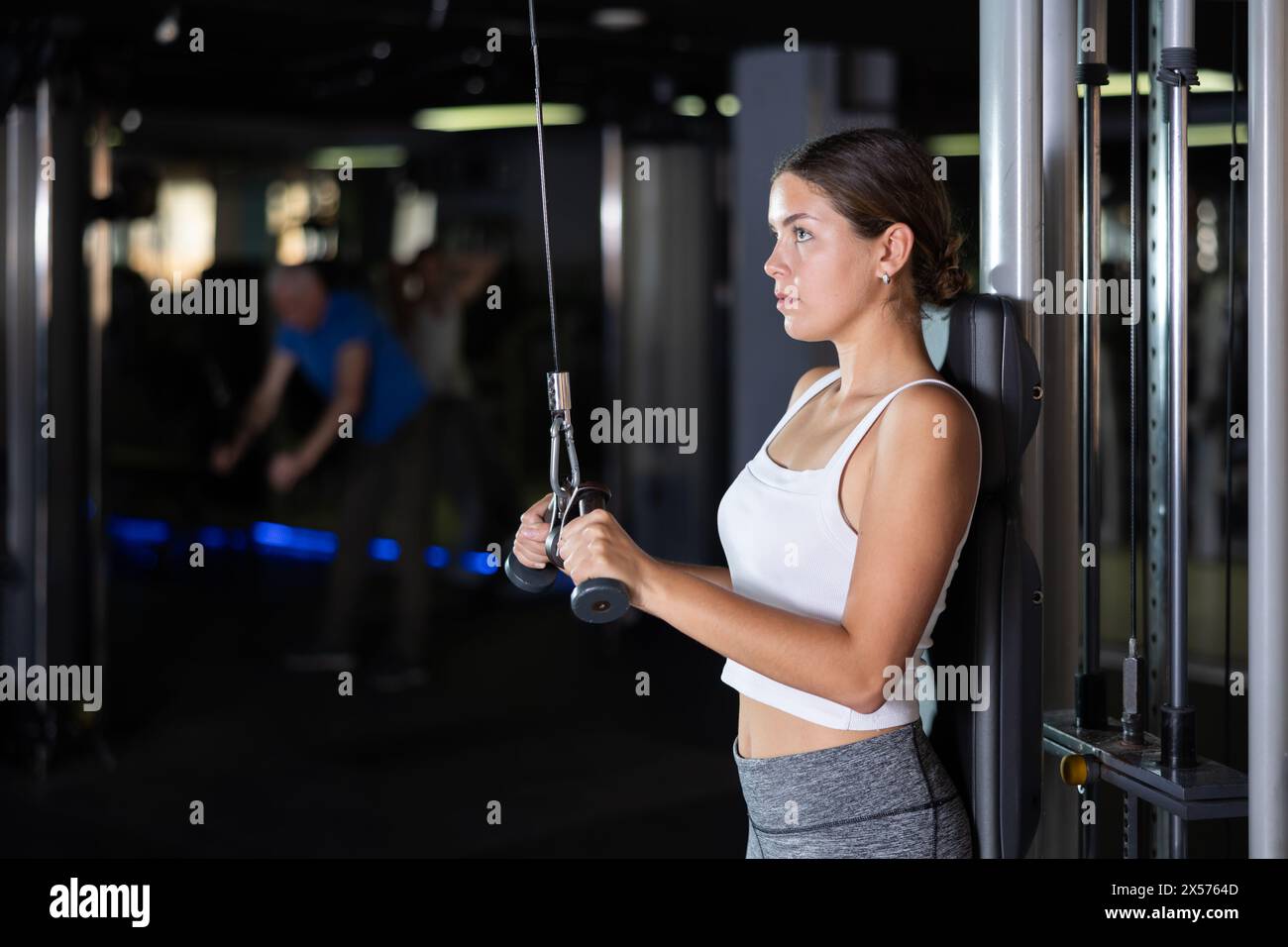 Athletic girl work out muscles of arms and shoulders on rope loop ...