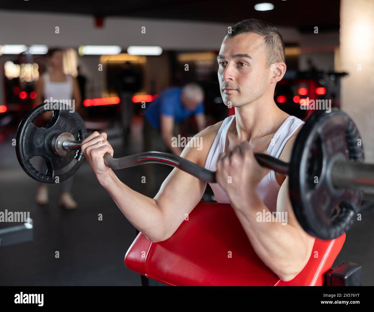 Sporty man performing set of exercises with barbell during intense ...