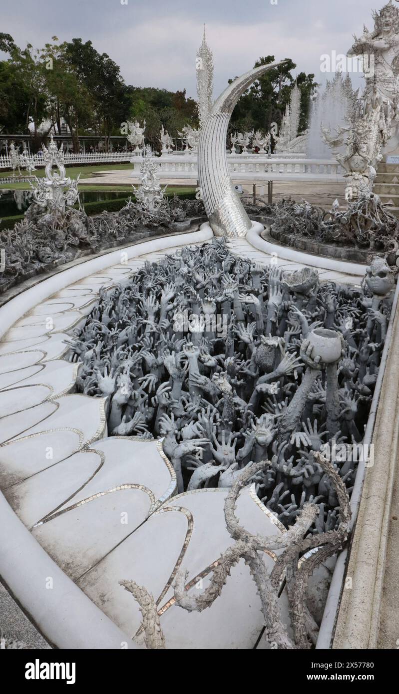 Sculptures of hands and faces reaching upward at the White Temple, Wat ...