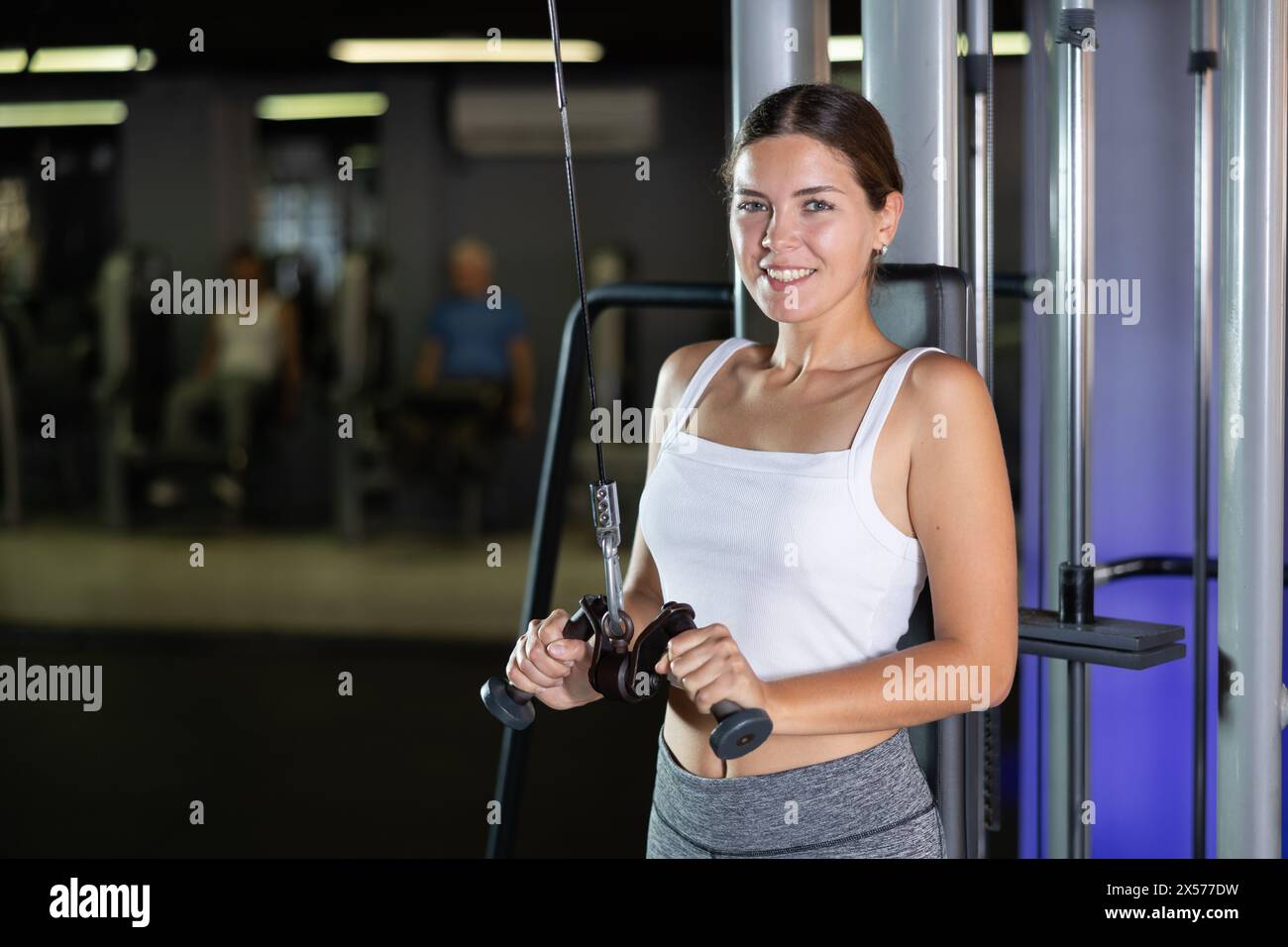 Athletic girl work out muscles of arms and shoulders on rope loop ...