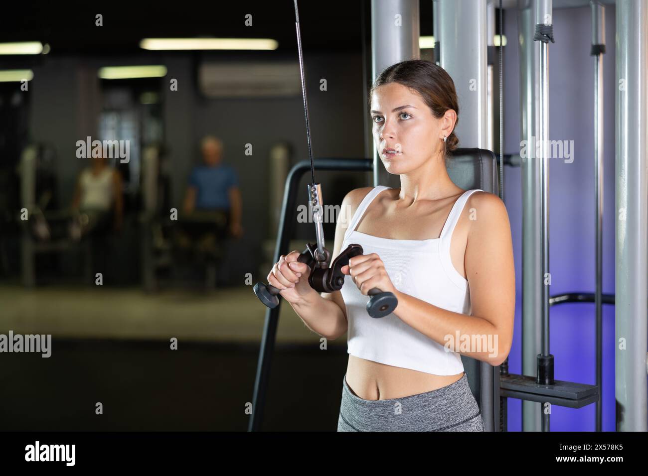 Athletic girl work out muscles of arms and shoulders on rope loop ...