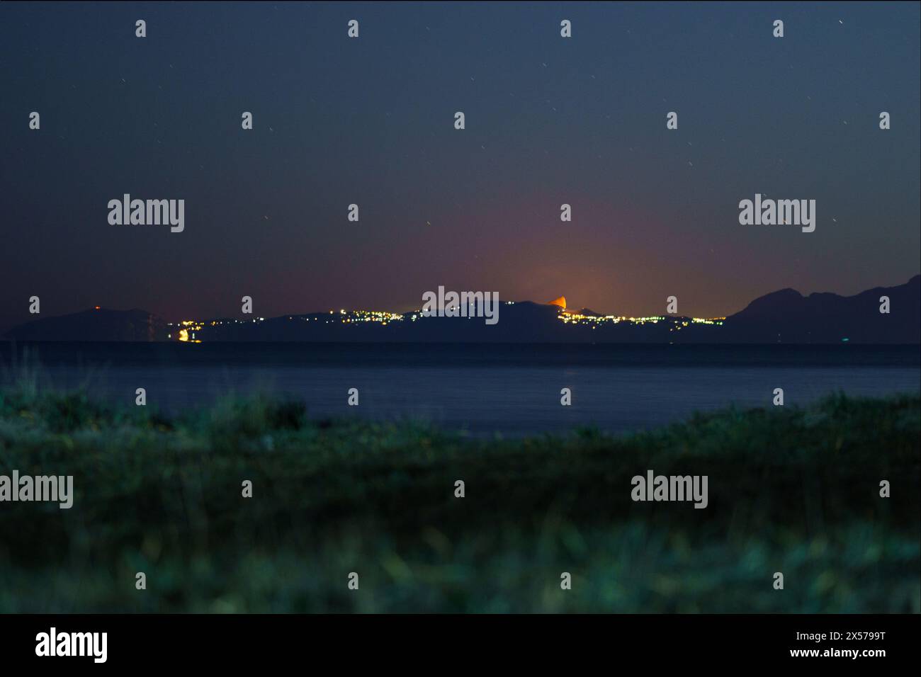 Crescent moon rising over illuminated Amalfi Coast at night, Paestum ...