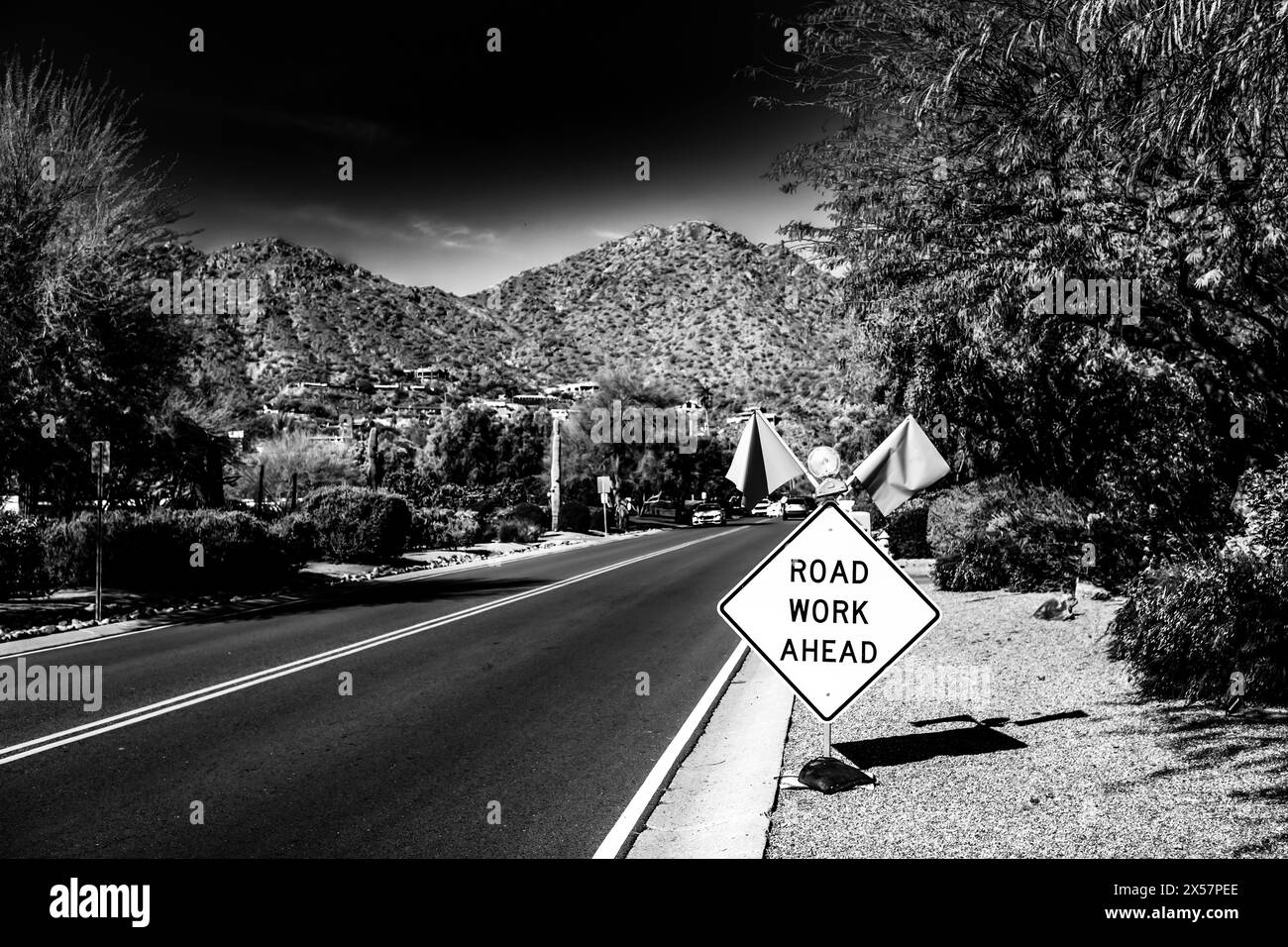 Road Work Ahead sign and flags posted on a road with construction in ...