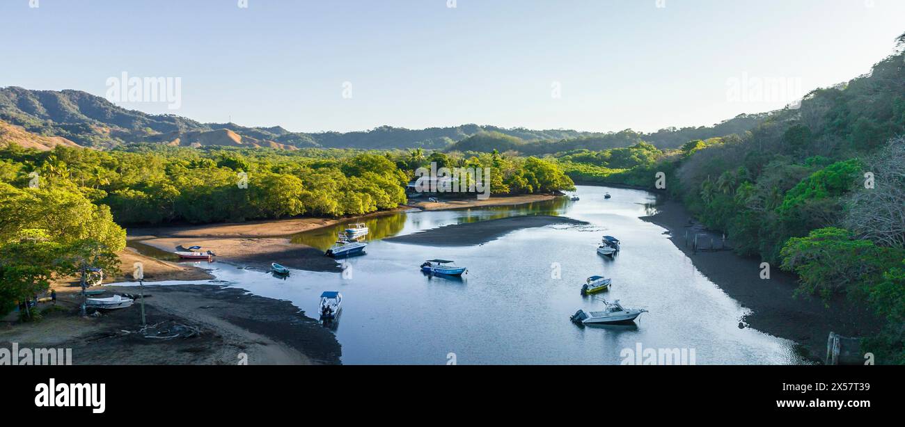 Aerial view of a peaceful estuary with boats surrounded by trees and ...