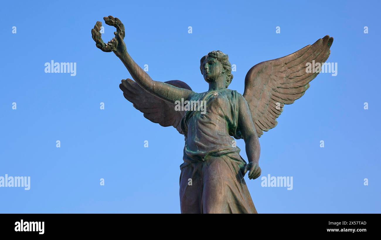 Statue of an angel with outspread wings in front of a blue sky, harbour ...