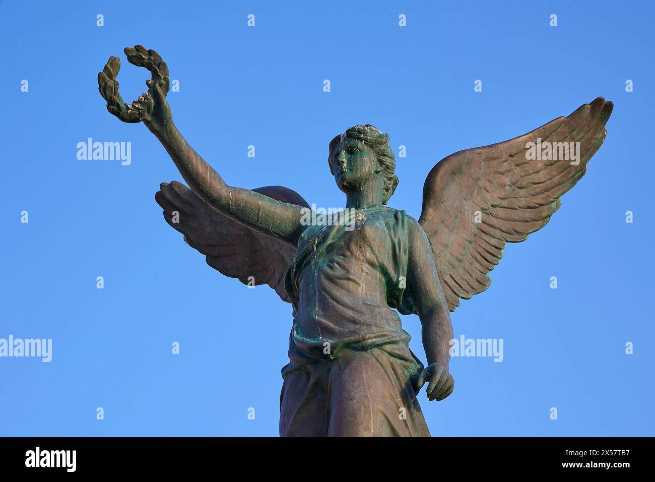 A statue of an angel with outstretched wings against a blue sky ...