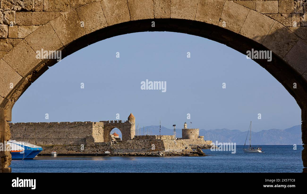 View through a stone window arch to the sea and a small castle in the ...