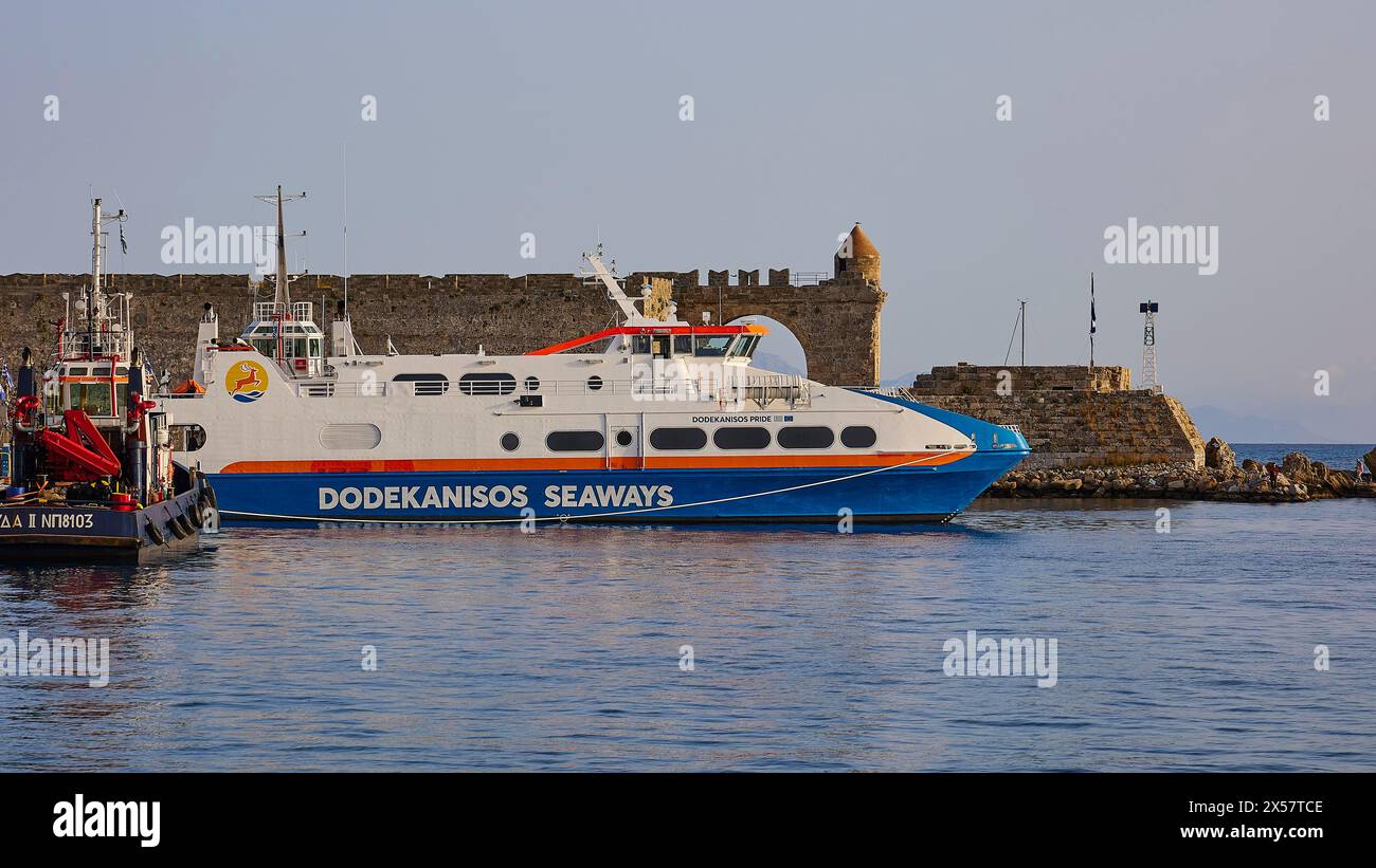 A white ferry lies in front of an old coastal fortification in the calm ...