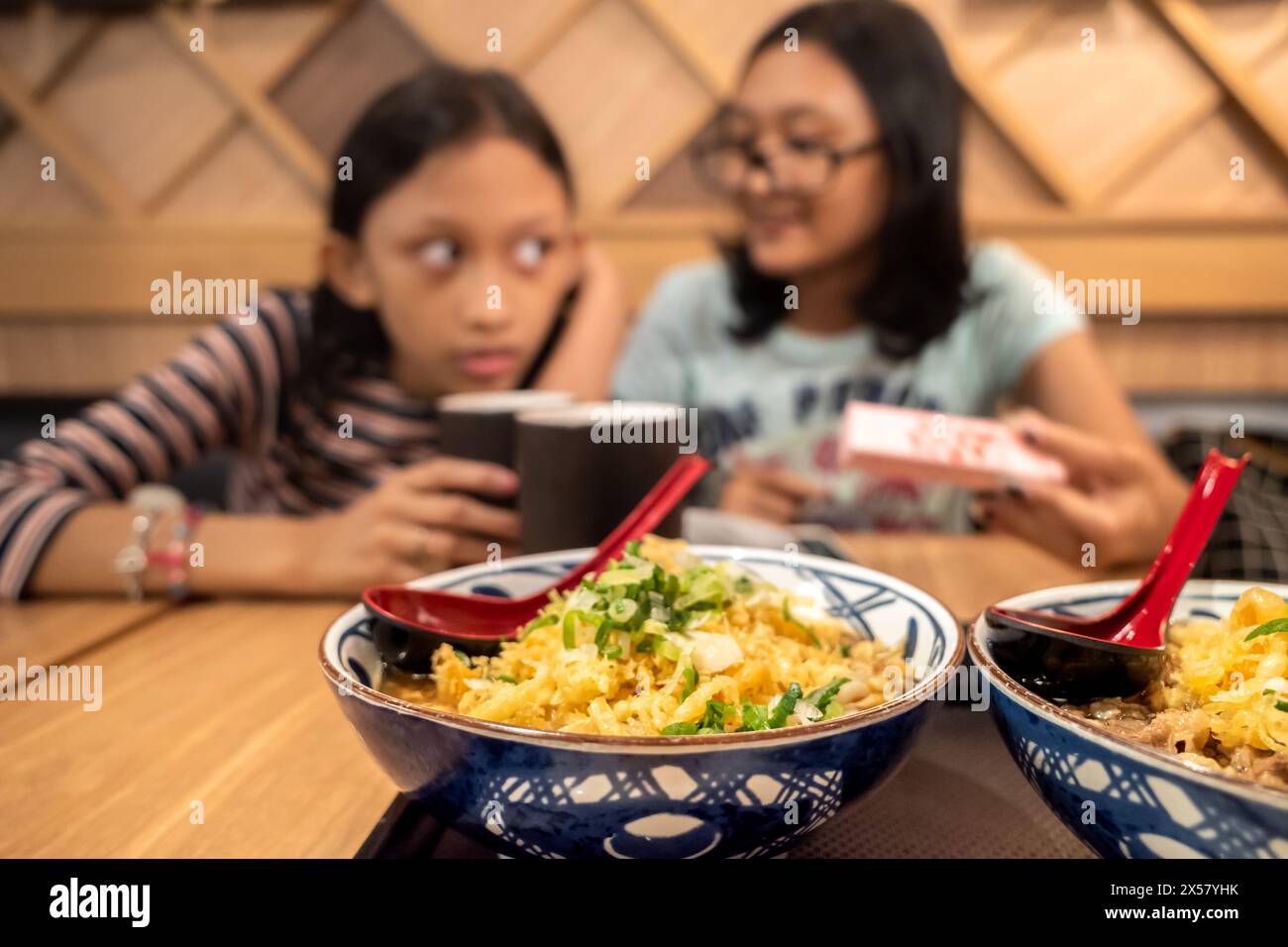 A bowl of noodle menu served at Japanese restaurant, with Asian teen ...