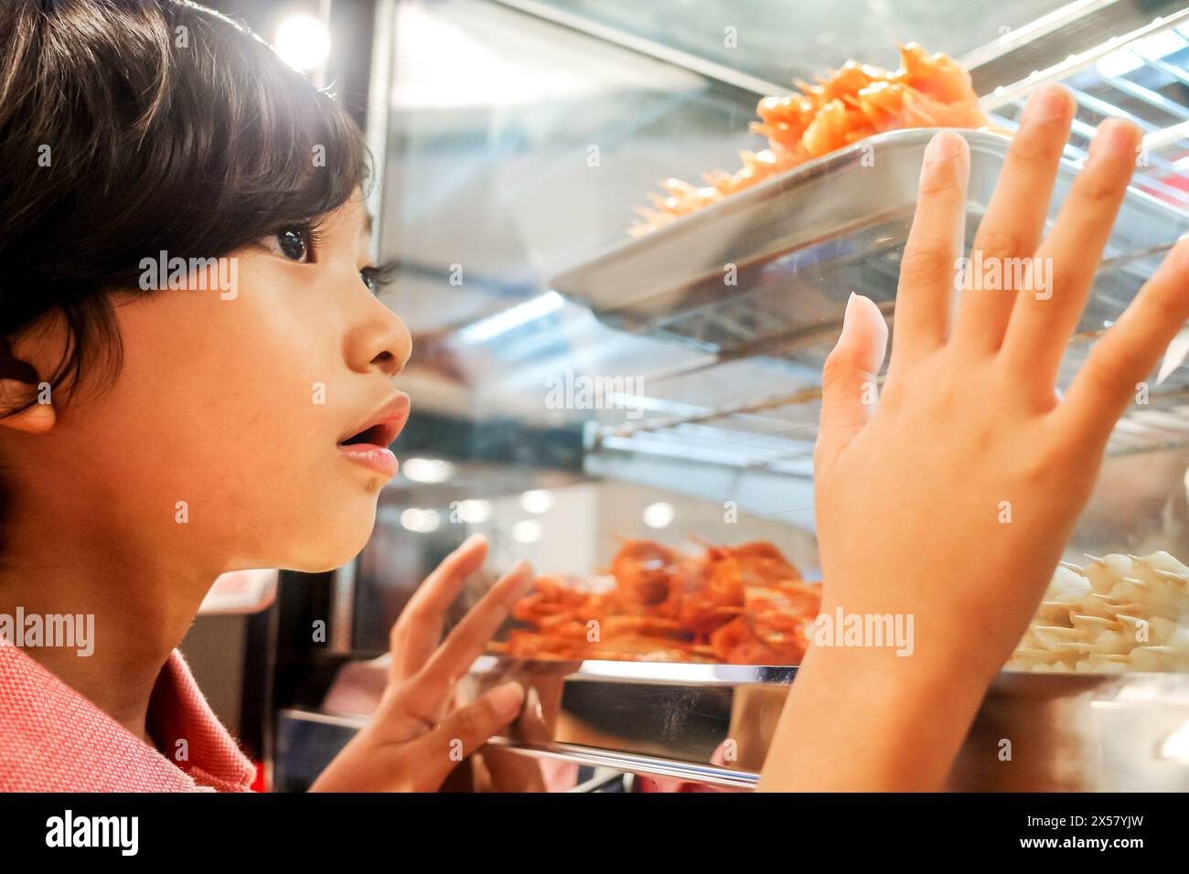 Asian little boy showing interest in snacks displayed at a local satay ...