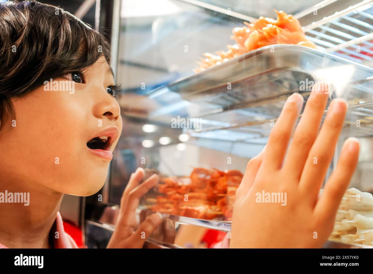 Asian little boy showing interest in snacks displayed at a local satay ...
