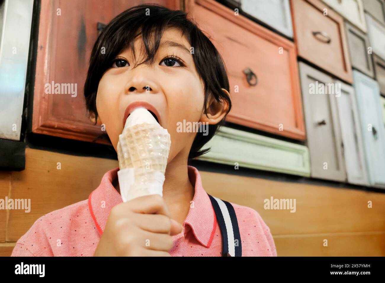 Southeast Asian boy enjoy eating vanilla ice cream cone at mall Stock ...