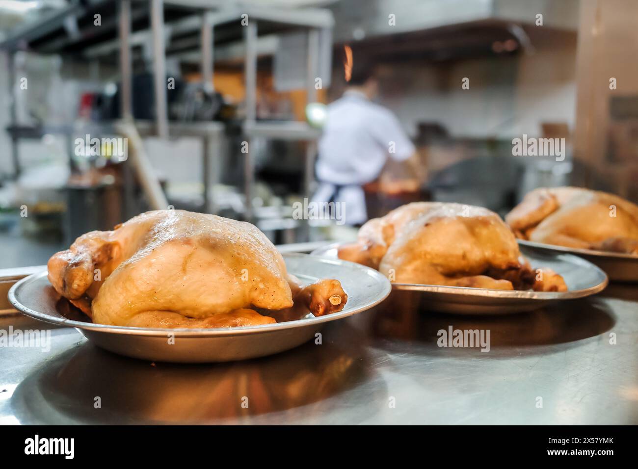 Chicken meat menu prepared in a restaurant kitchen with chef and staff ...