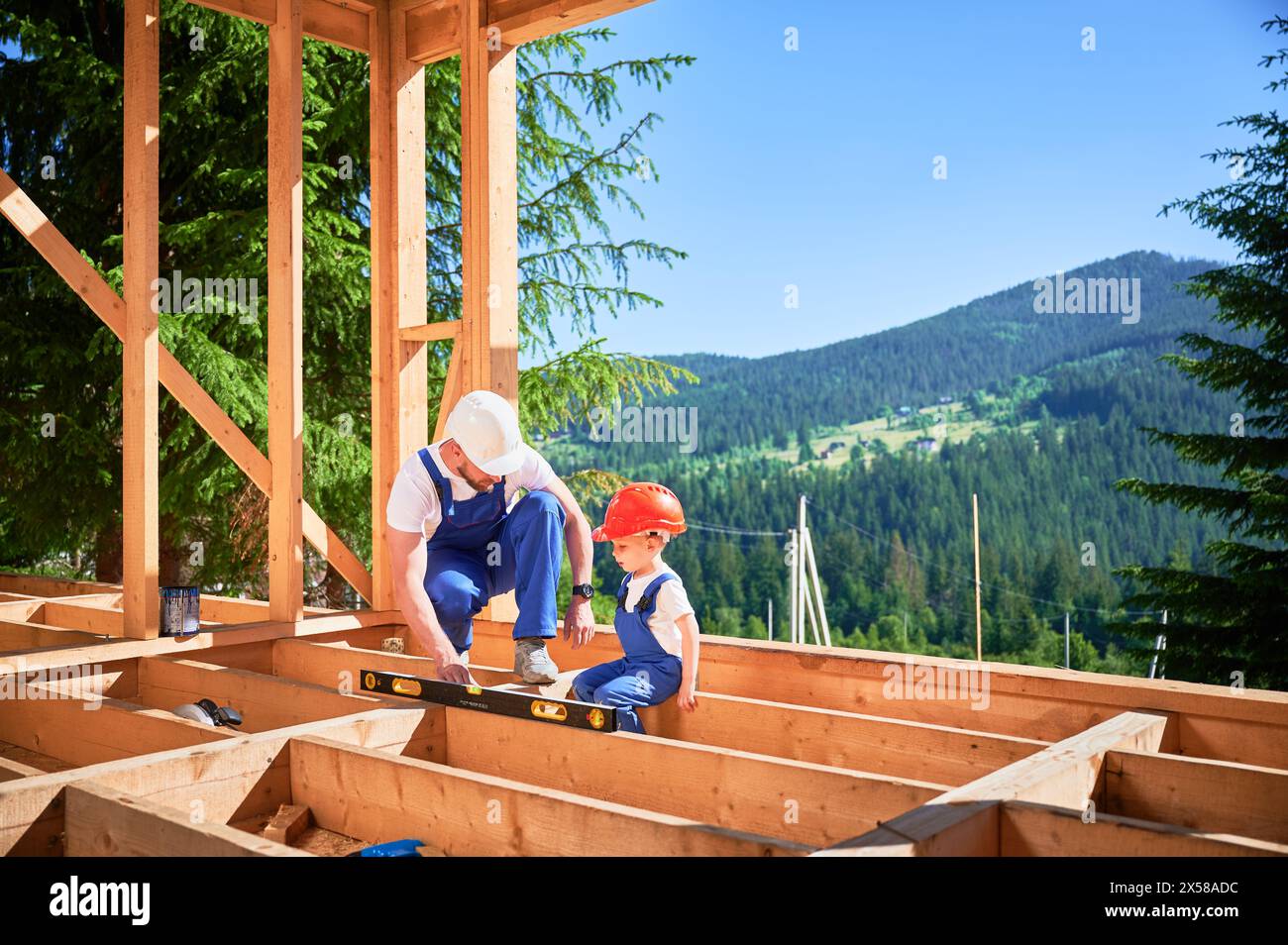 Father with toddler son building wooden frame house. Male builder ...