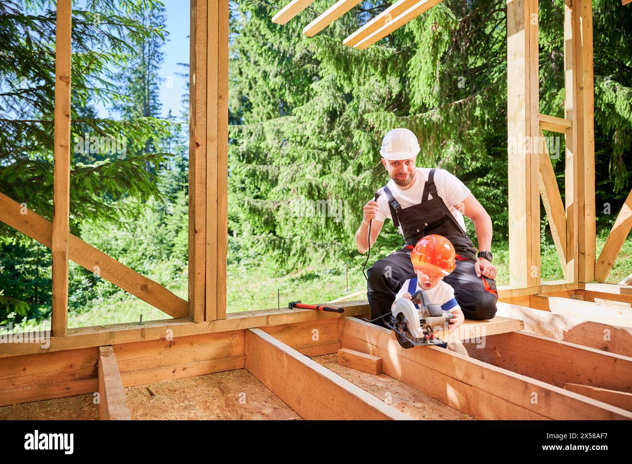 Father with toddler son building wooden frame house. Man playing with ...