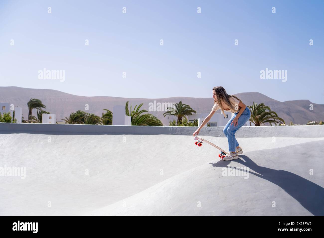 A young woman riding a skateboard down the side of a ramp with a ...
