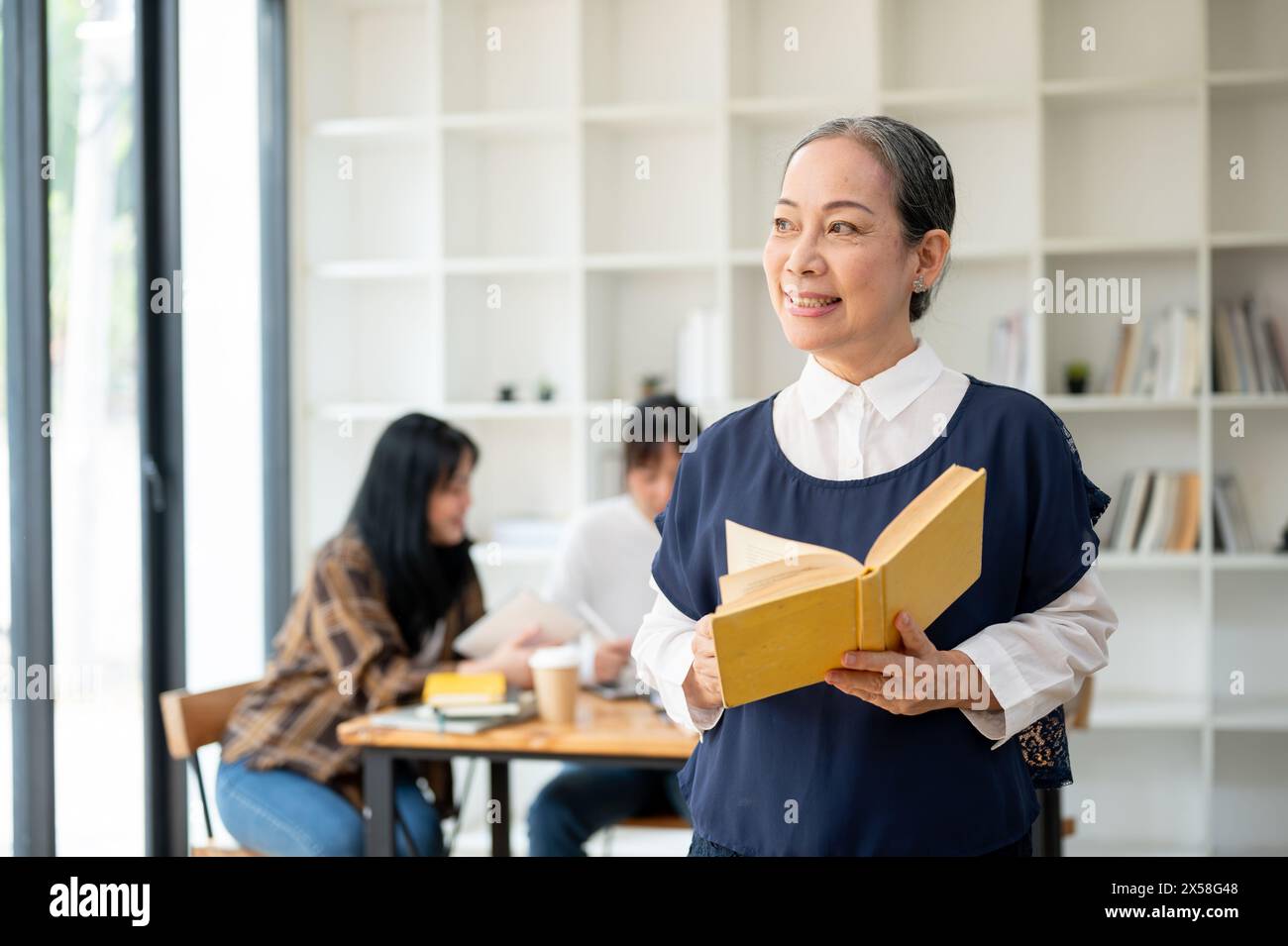 A portrait of a smiling, satisfied senior Asian female teacher ...