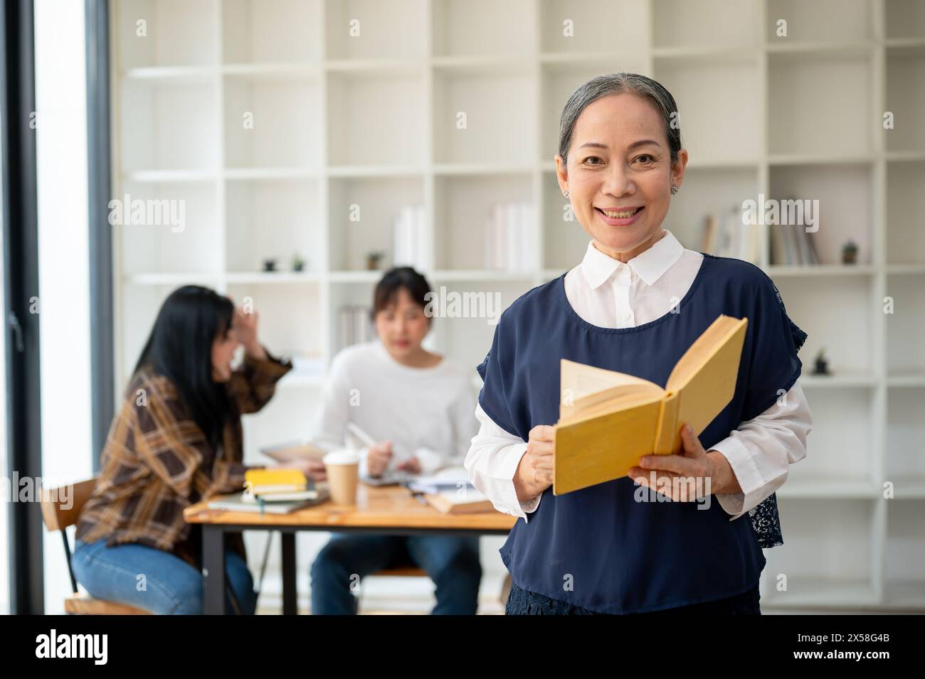 A portrait of a smiling, satisfied senior Asian female teacher ...
