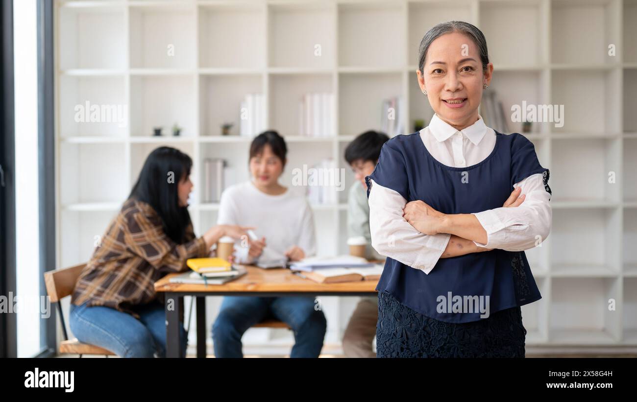 A portrait of a smiling, satisfied senior Asian female teacher ...