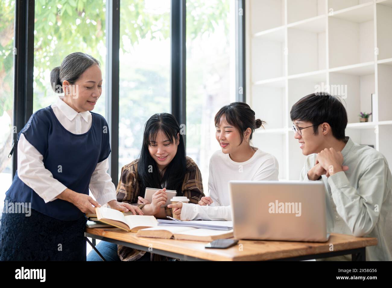 A positive and kind senior Asian female teacher is teaching her ...