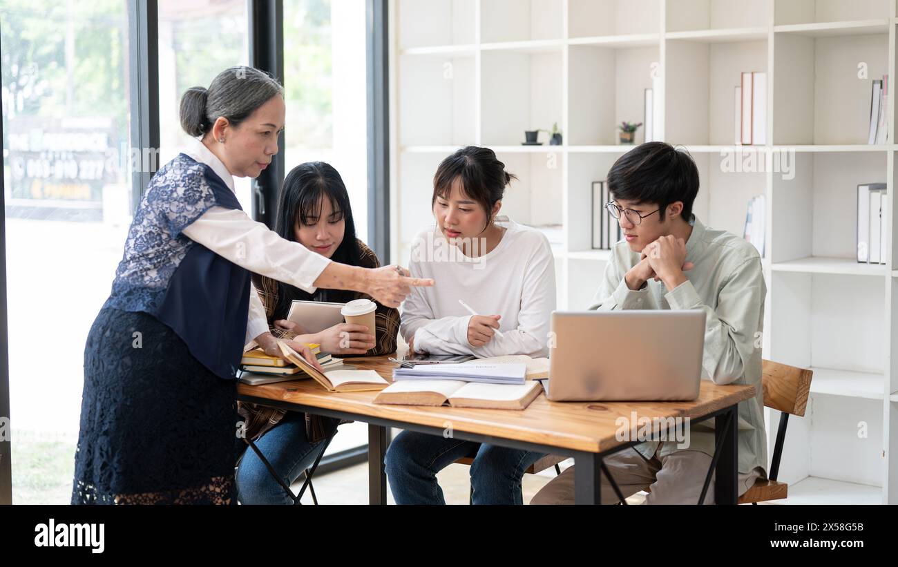 A mature Asian female teacher professor is giving a lecture to her students in the classroom ...
