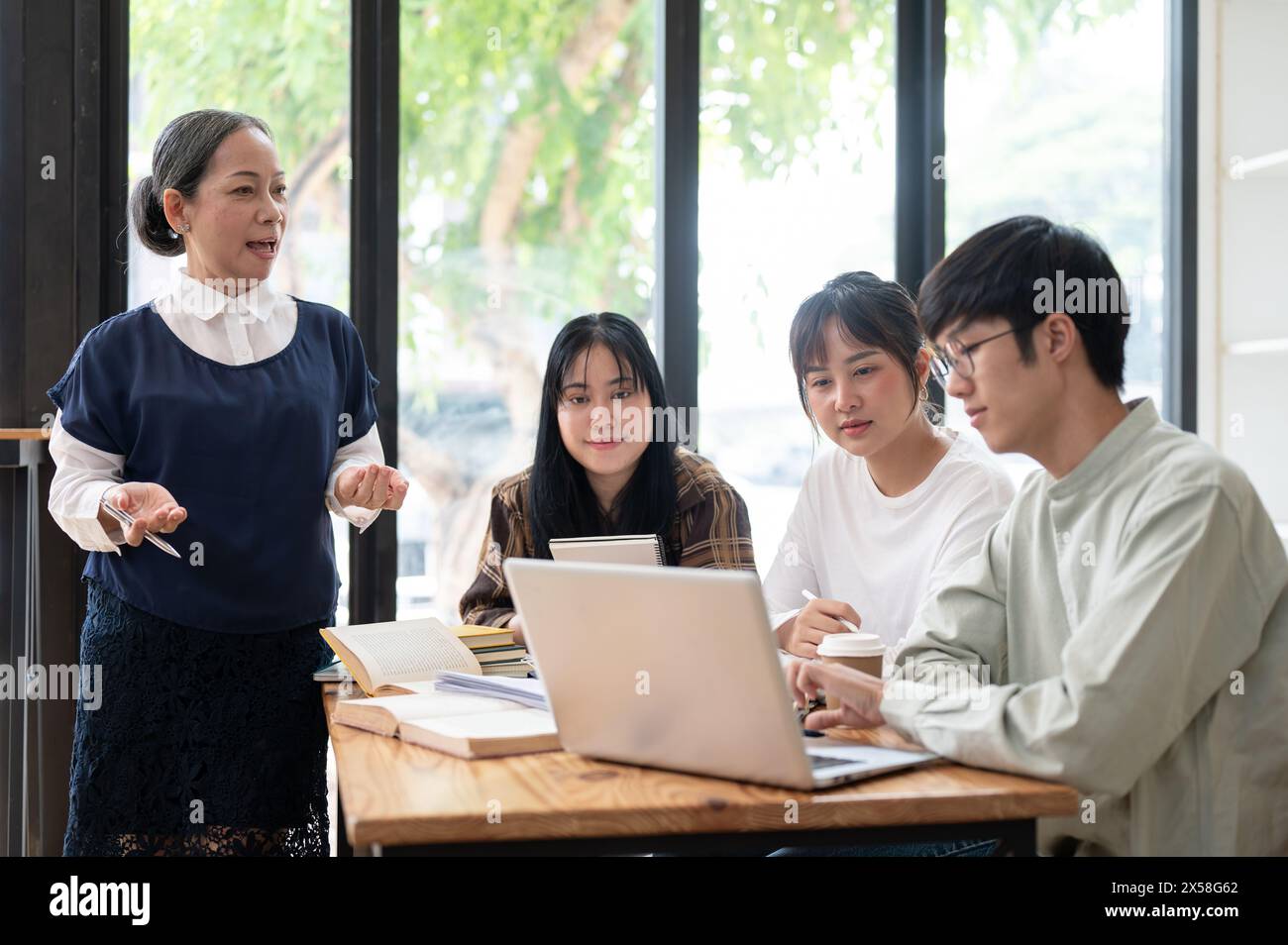 A mature Asian female teacher professor is giving a lecture to her ...