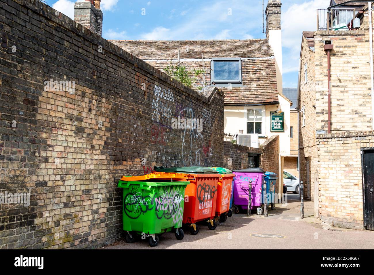 Colorful waste bins lined up against a brick wall along Milton's Walk ...