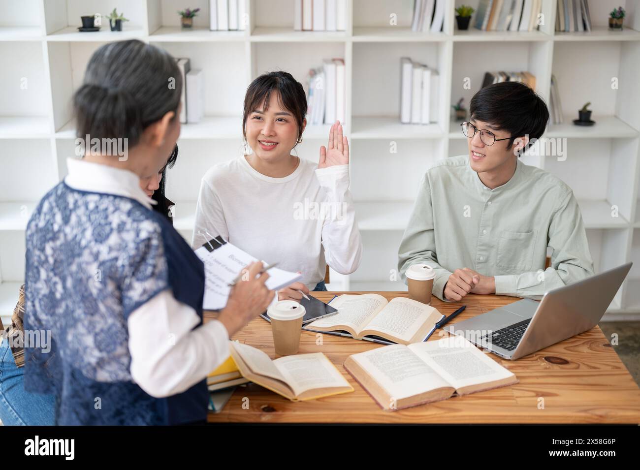 A positive young Asian female university student is raising her hand ...