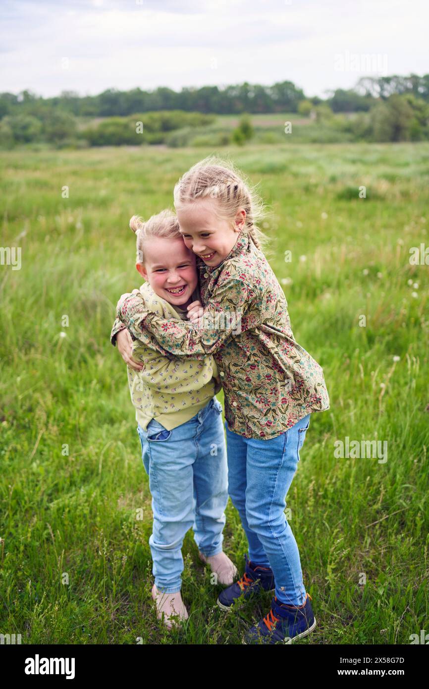 sisters hug and protect each other from the wind in the field Stock ...
